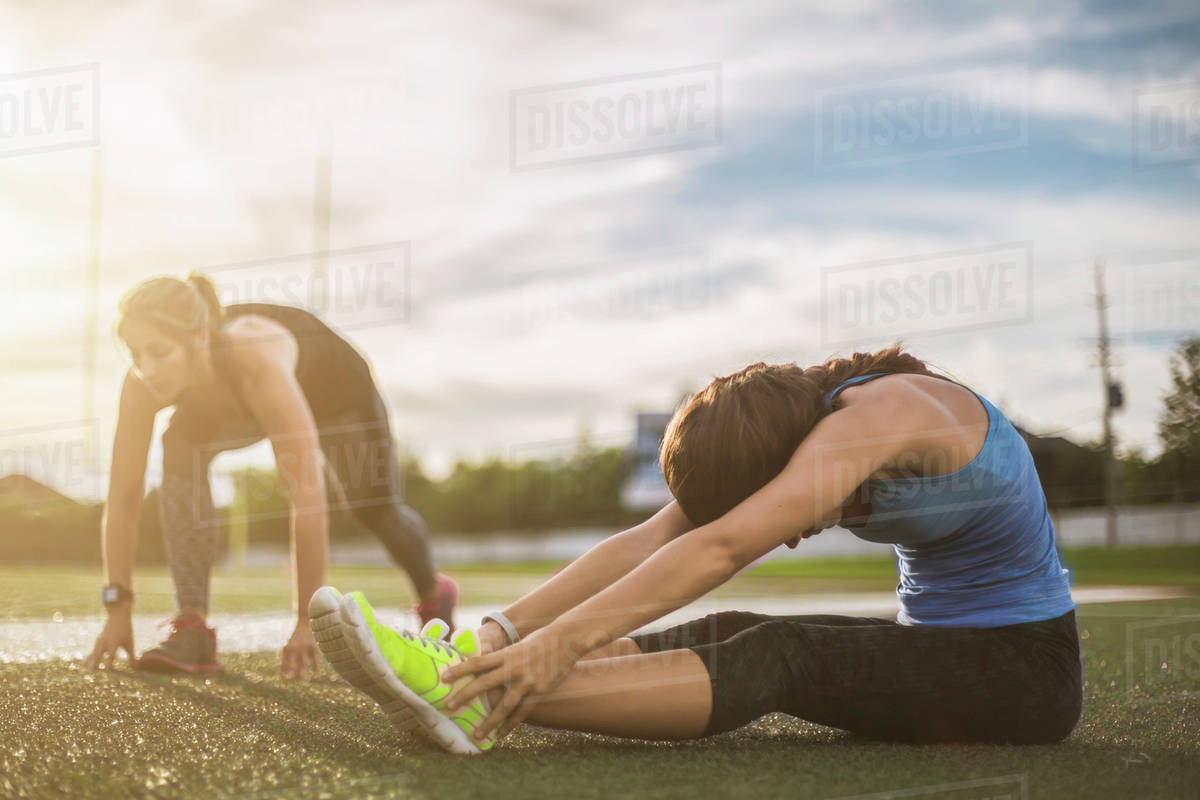 Athletes stretching on sports field - Stock Photo - Dissolve