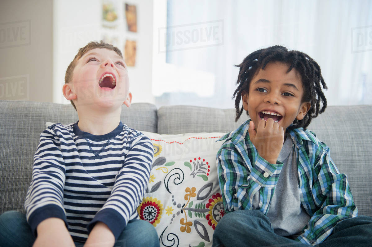 Boys laughing on living room sofa - Royalty-free Stock Photo | Dissolve