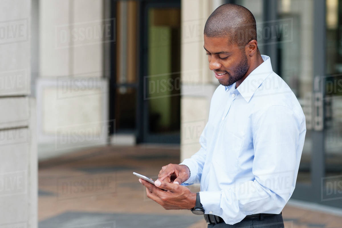 Black businessman using cell phone outside office - Royalty-free Stock ...