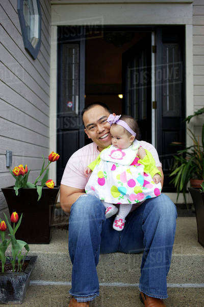 Father sitting on front stoop with baby girl - Stock Photo - Dissolve
