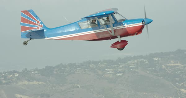 Helicopter aerial shot of small plane moving slowly away over ocean and ...
