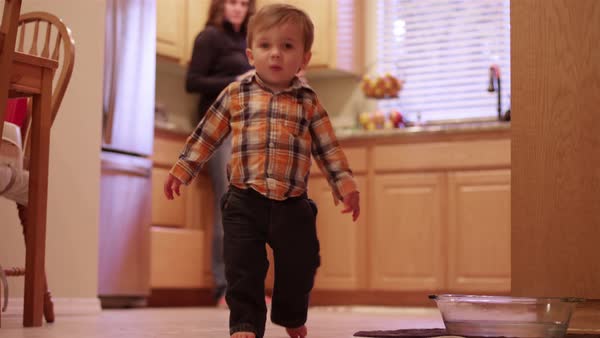 A little boy walking through the kitchen and living room to play with ...
