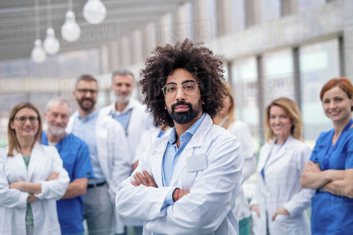 Group of doctors standing in corridor on medical conference, looking at ...