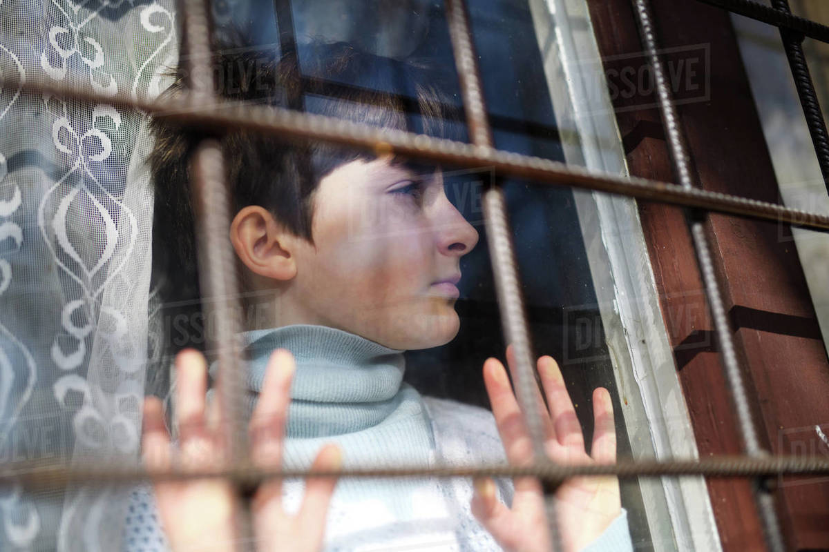 Poor sad small girl standing by window indoors at home, poverty and ...