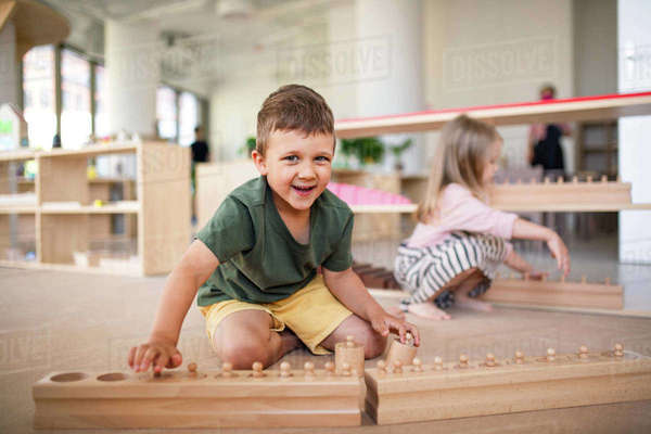 A group of small nursery school children playing indoors in classroom ...