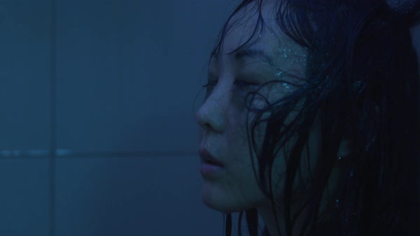 Close-up shot of a depressed young woman standing under shower at home ...