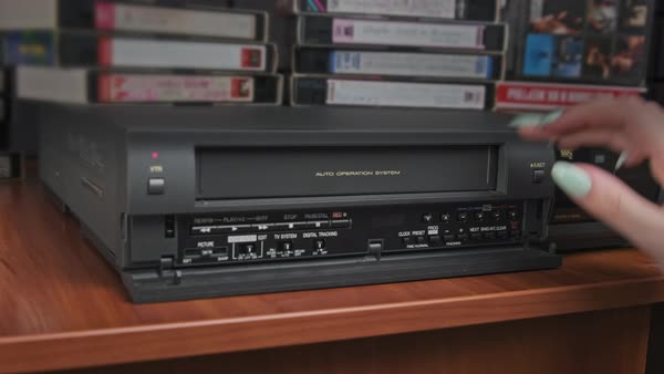 Eject VHS tape cassette from VCR player. Man pulls out VHS from vintage ...