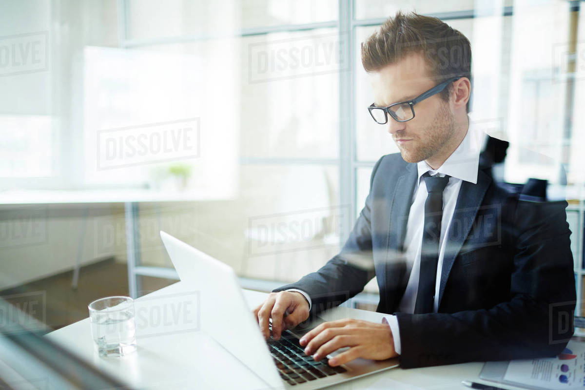 Handsome employee typing at workplace - Royalty-free Stock Photo | Dissolve