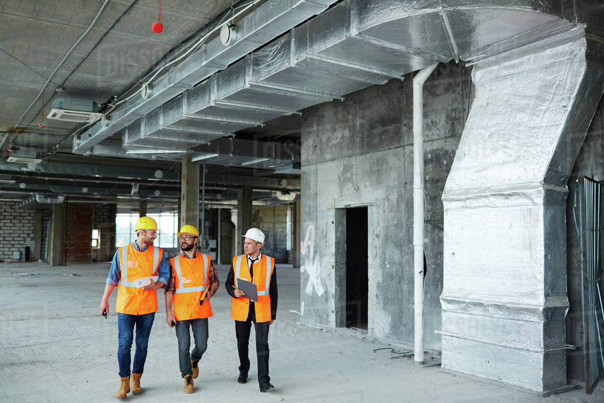 Team of engineers moving down construction site and talking - Stock ...