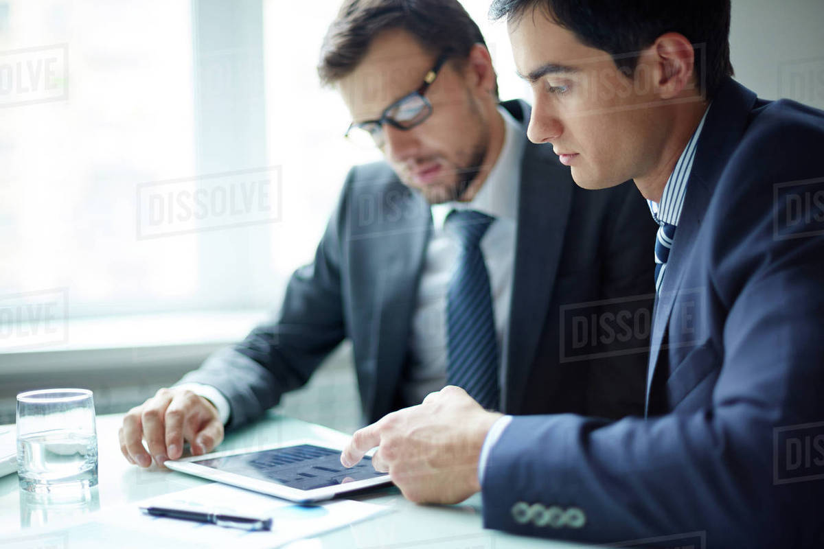Two businessmen sitting at the table and using tablet pc - Royalty-free ...