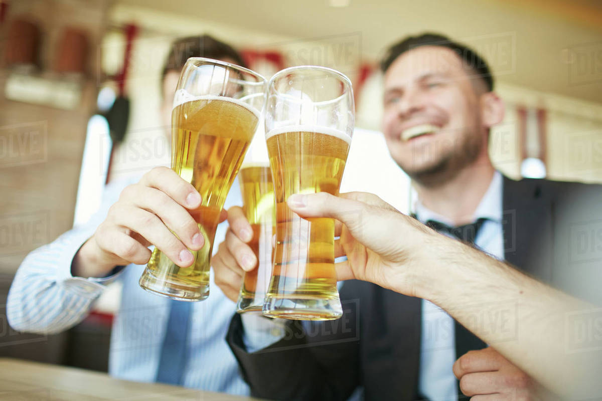 Happy young men clinking with glasses of beer - Royalty-free Stock ...