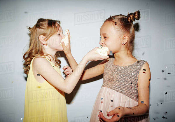 Two little girls giving a piece of cake to each other - Royalty-free ...