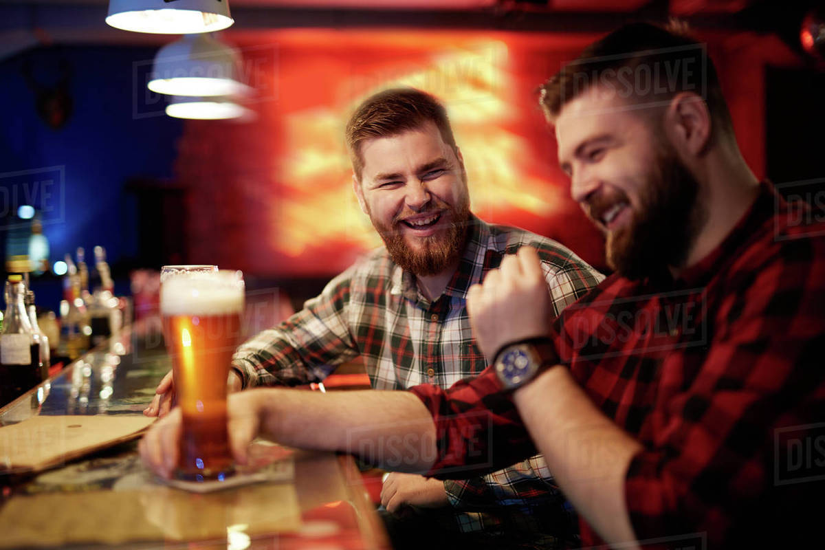 Friendly young men with beer talking in pub - Royalty-free Stock Photo ...