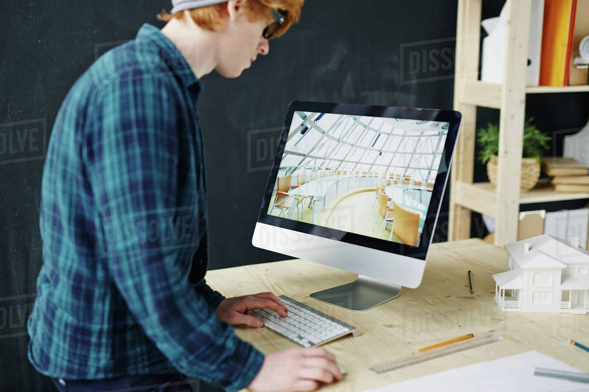 Architect standing in front of monitor with image of business hall ...