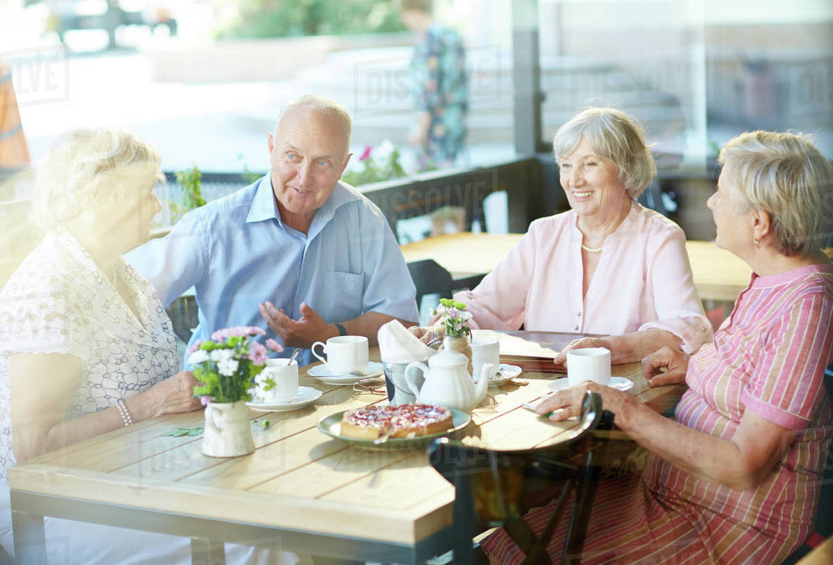 Seniors talking in cafe on sunny day - Royalty-free Stock Photo | Dissolve