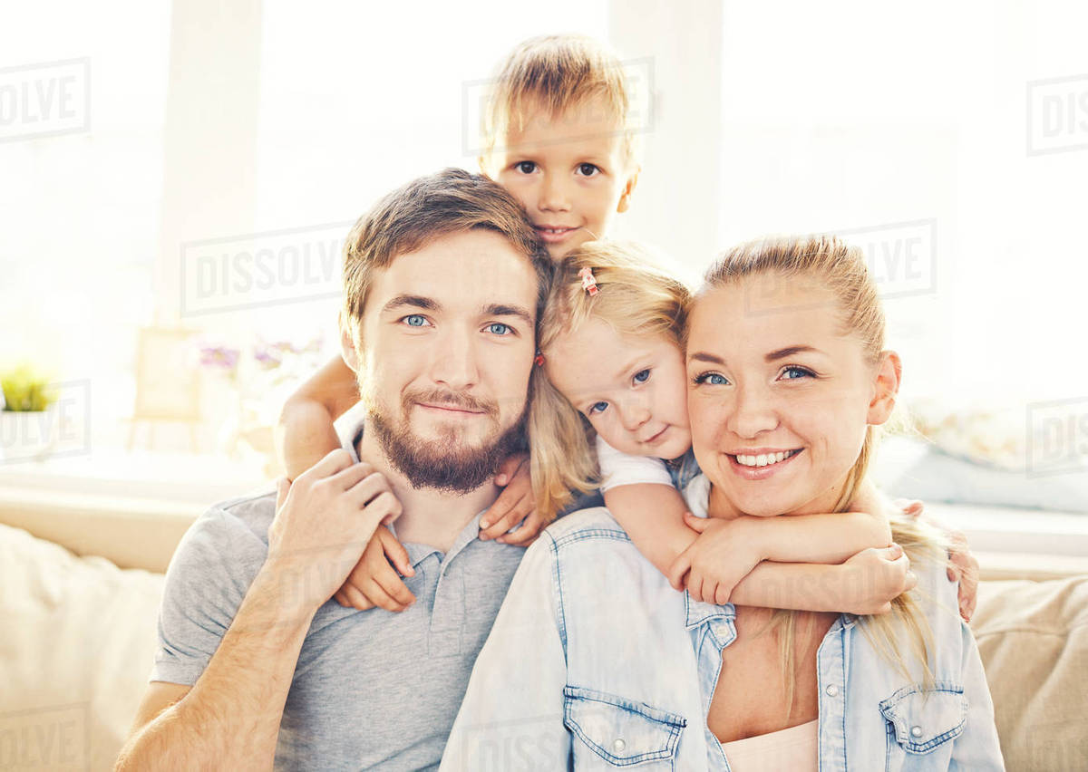 Smiling parents with two children looking at camera - Stock Photo ...