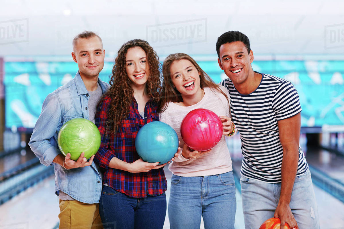 Portrait of two couples playing bowling - Stock Photo - Dissolve