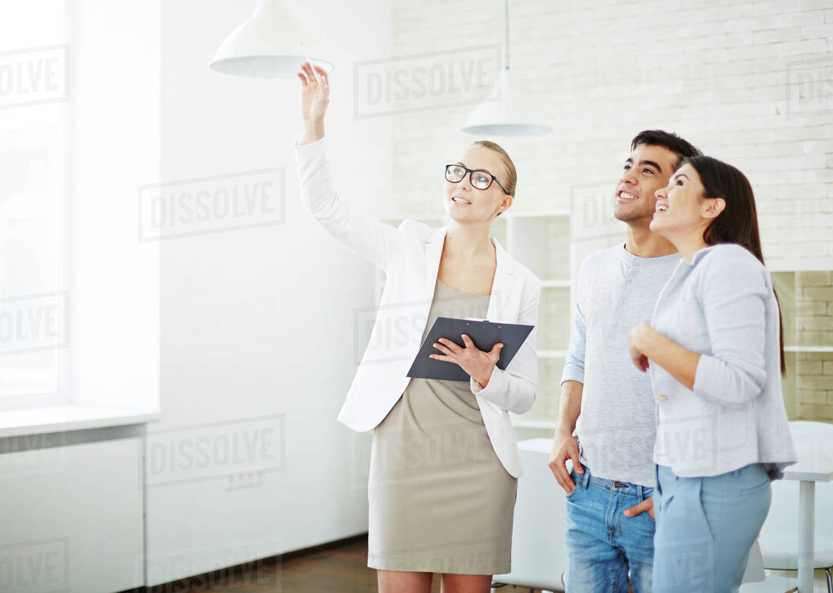 Female realtor showing room to young couple - Royalty-free Stock Photo ...