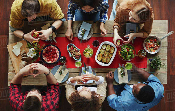 High angle view of young people sitting at table and having dinner ...