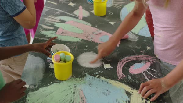 Close up multi ethnic children drawing coloring space pictures together ...