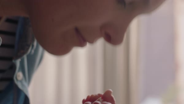 Close up mother holding baby feet playfully kissing toes nurturing ...