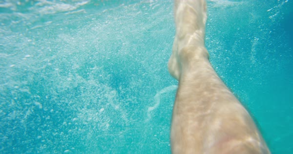 Feet floating in ocean waves from underwater light rays shining through ...