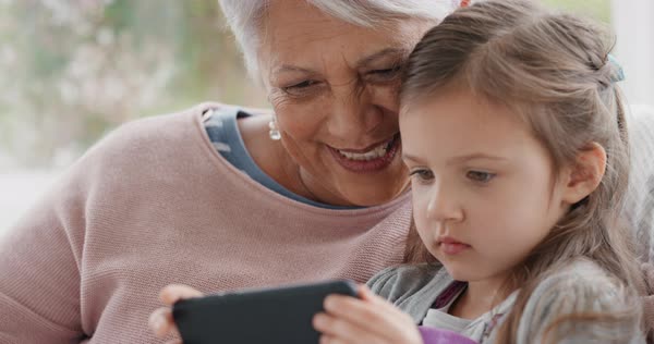 Little girl showing grandmother how to use smartphone teaching granny ...