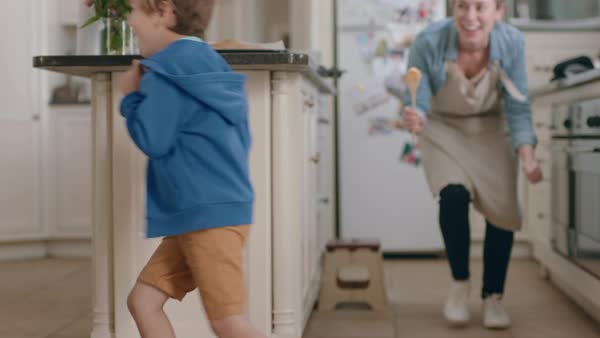Happy mother and son playing in kitchen mom chasing little boy running ...