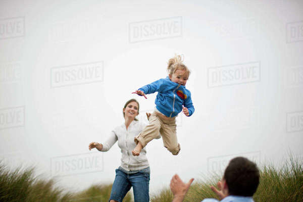 Happy young girl leaping into the arms of her father on a beach ...