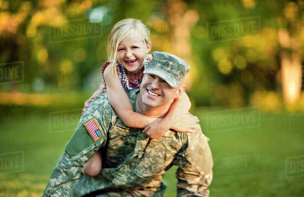 Portrait of a smiling army soldier giving his young daughter a piggy ...