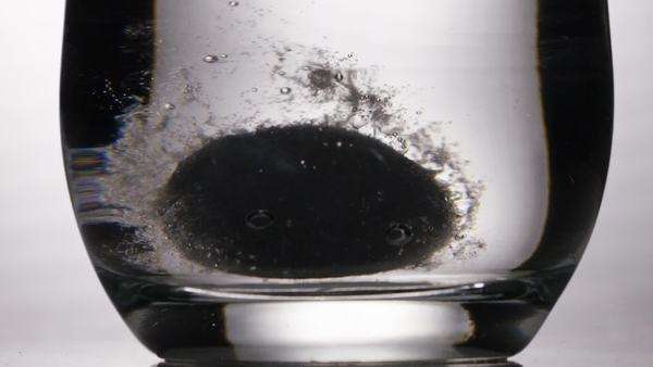 Dissolving tablet dropped into a glass of water, in slow motion - Stock ...