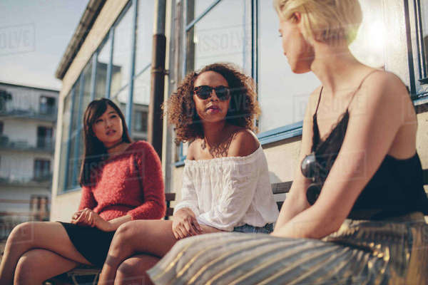 Three young female friends meeting outdoors. Multiracial group of young ...