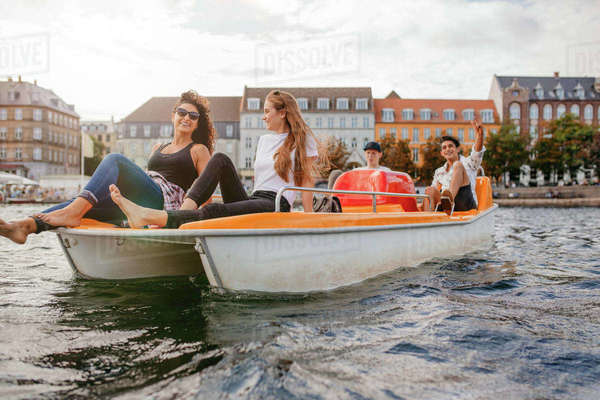 Shot of group of young friends enjoying a ride on pedal boat. Teenagers ...
