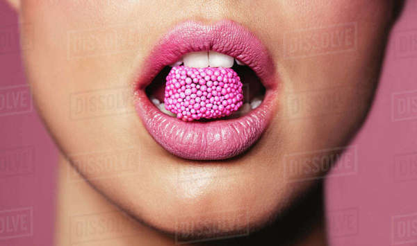 Beautiful pink lips with a piece of sweet candy. Close up of young ...