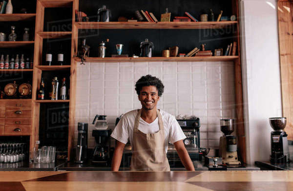 Portrait of professional barista standing at cafe counter. African man ...