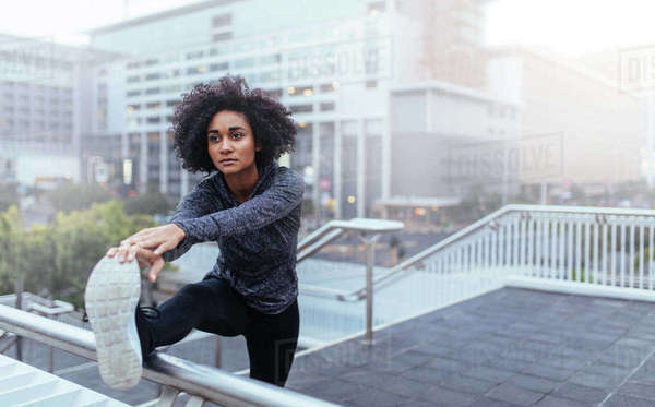 Woman runner doing stretching exercises. Woman using stair railing for ...