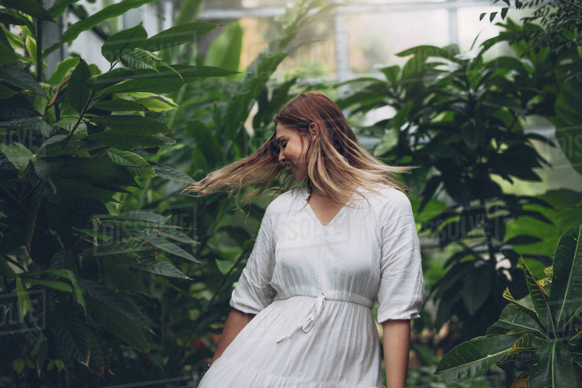 Beautiful young woman standing in tropical botanical garden. Female ...