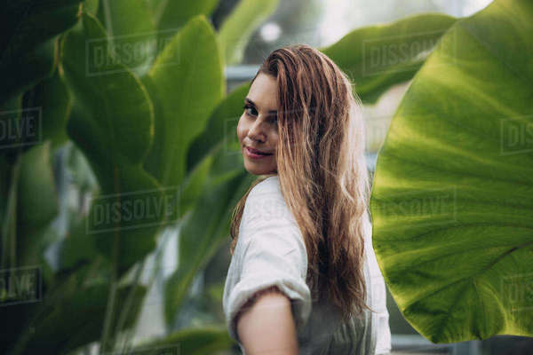 Portrait of beautiful model in greenhouse looking at camera. Female ...