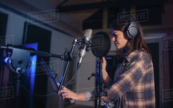 Woman recording music in a professional recording studio. Female singer ...