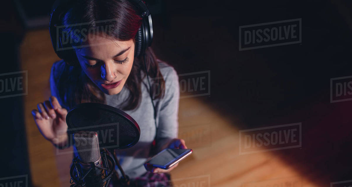 Close up of female singer singing song in recording studio. Top view of ...