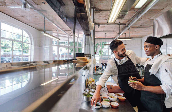 Professional chefs working in restaurant kitchen. Smiling chefs cooking ...