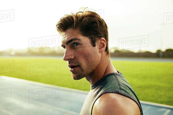 Closeup of a sprinter standing on a running track. Runner looking away ...