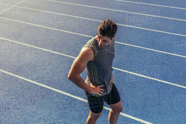 Athlete walking on a running track listening to music. Runner wearing ...