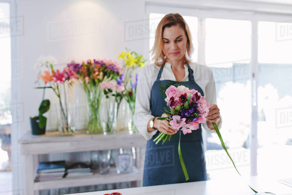 Female florist at work preparing a bouquet. Woman standing at counter ...
