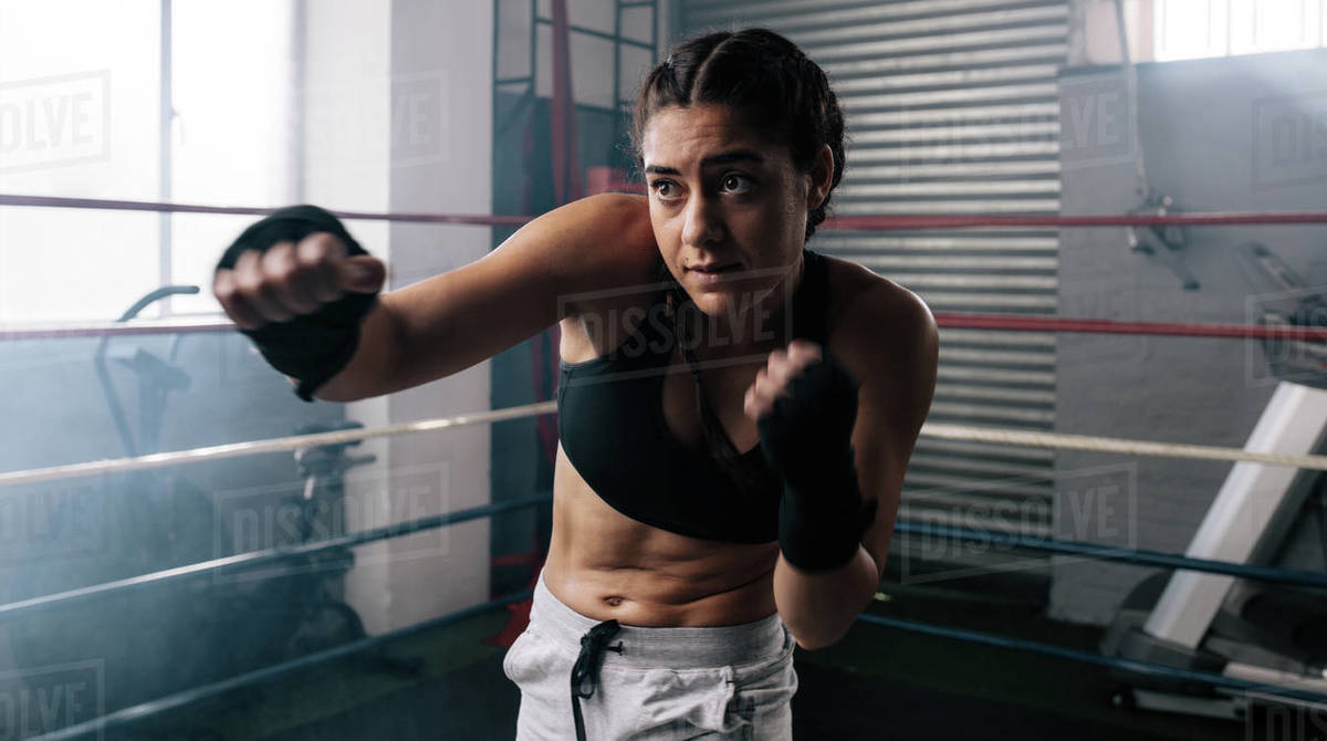 Female boxer doing shadow boxing inside a boxing ring. Boxer practicing ...