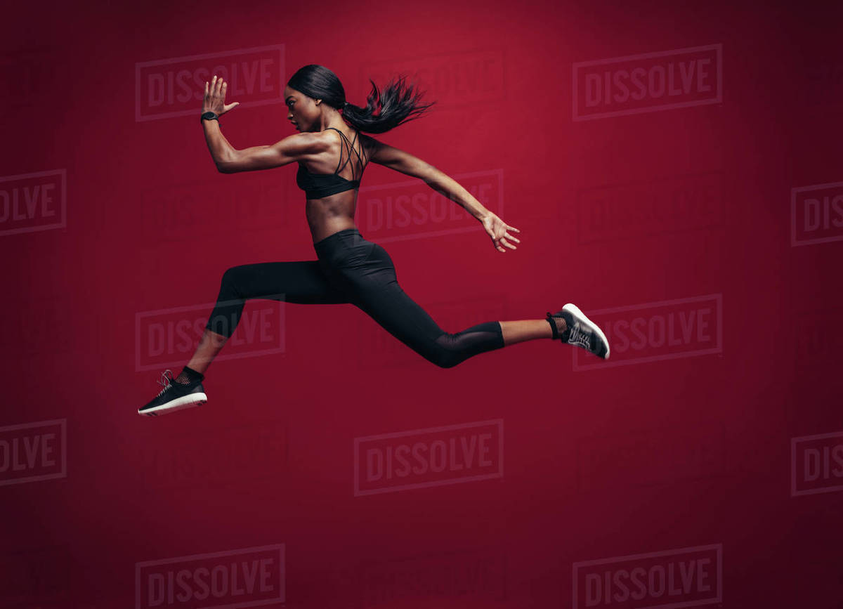 Female athlete running and jumping. Side view shot of healthy african ...