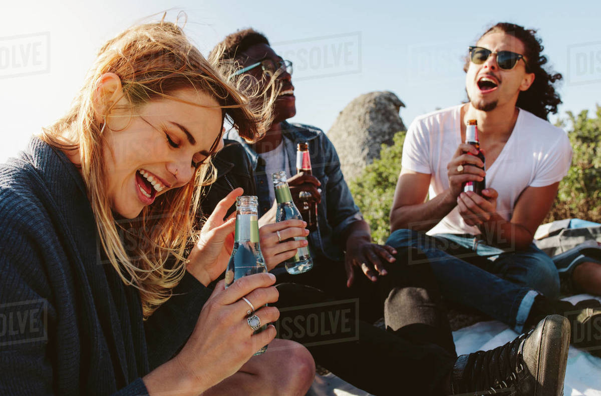 Group of friends having beers while sitting on mountain top. Cheerful ...