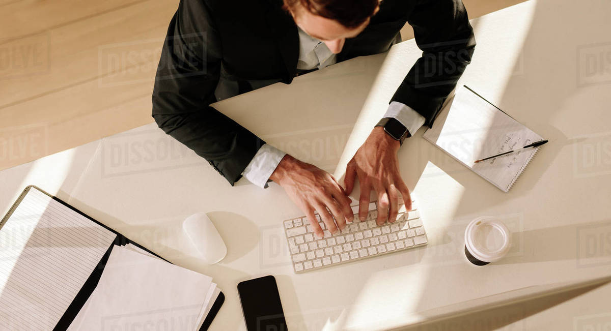 Top view of a businessman entering text in computer using keyboard with ...