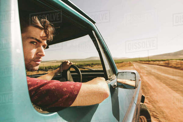 Close up of a man looking out of the window while driving a car. Man ...