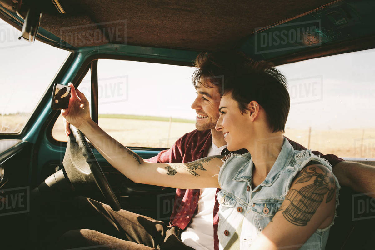 Cheerful young couple on a road trip enjoying the ride. Man and woman ...